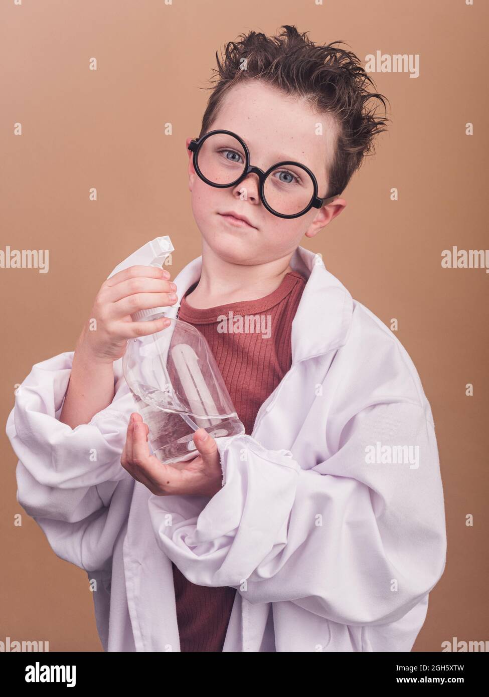 Chemist child in decorative glasses and laboratory robe looking at ...
