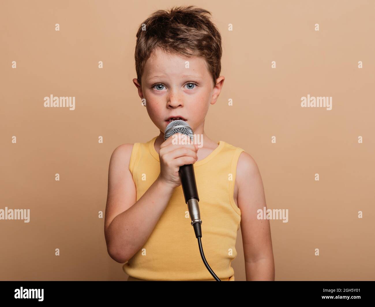 Cool child in singing in modern mic on brown background in studio Stock ...