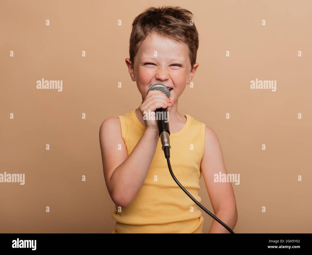 Cool child in singing in modern mic on brown background in studio Stock ...