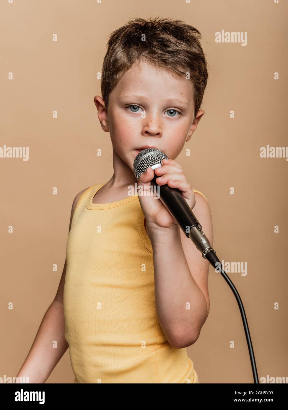Cool child in singing in modern mic on brown background in studio Stock ...