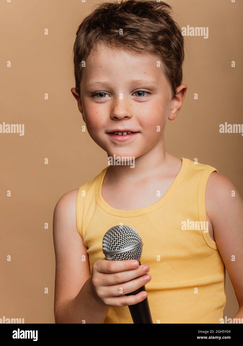 Cool child in singing in modern mic on brown background in studio Stock ...