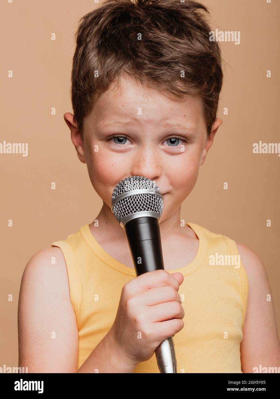 Cool child in singing in modern mic on brown background in studio Stock ...