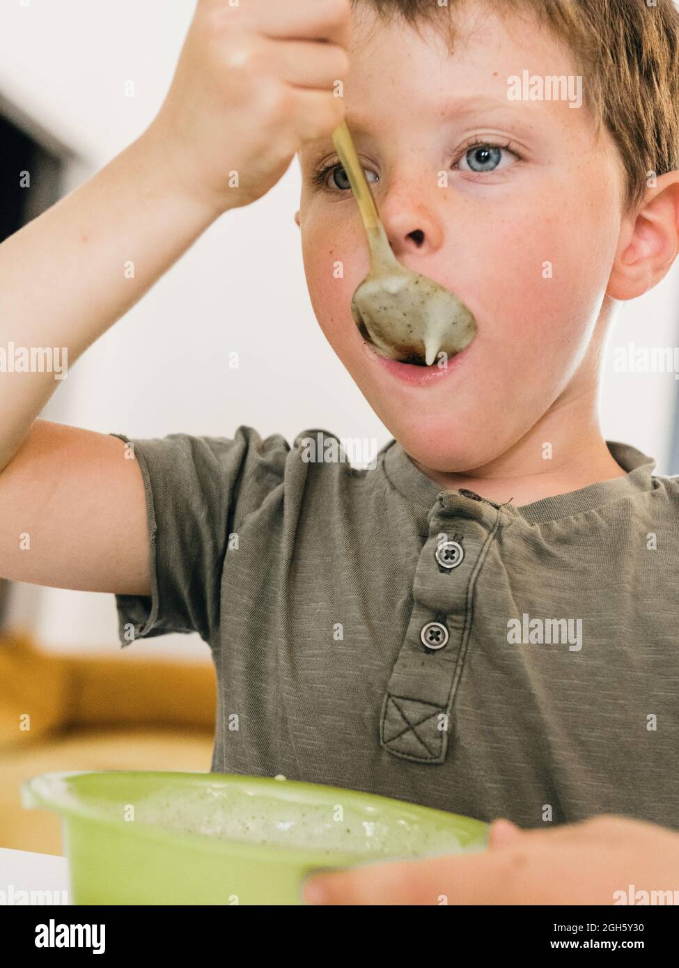 Adorable boy eating appetizing cream soup with spoon during lunch at ...