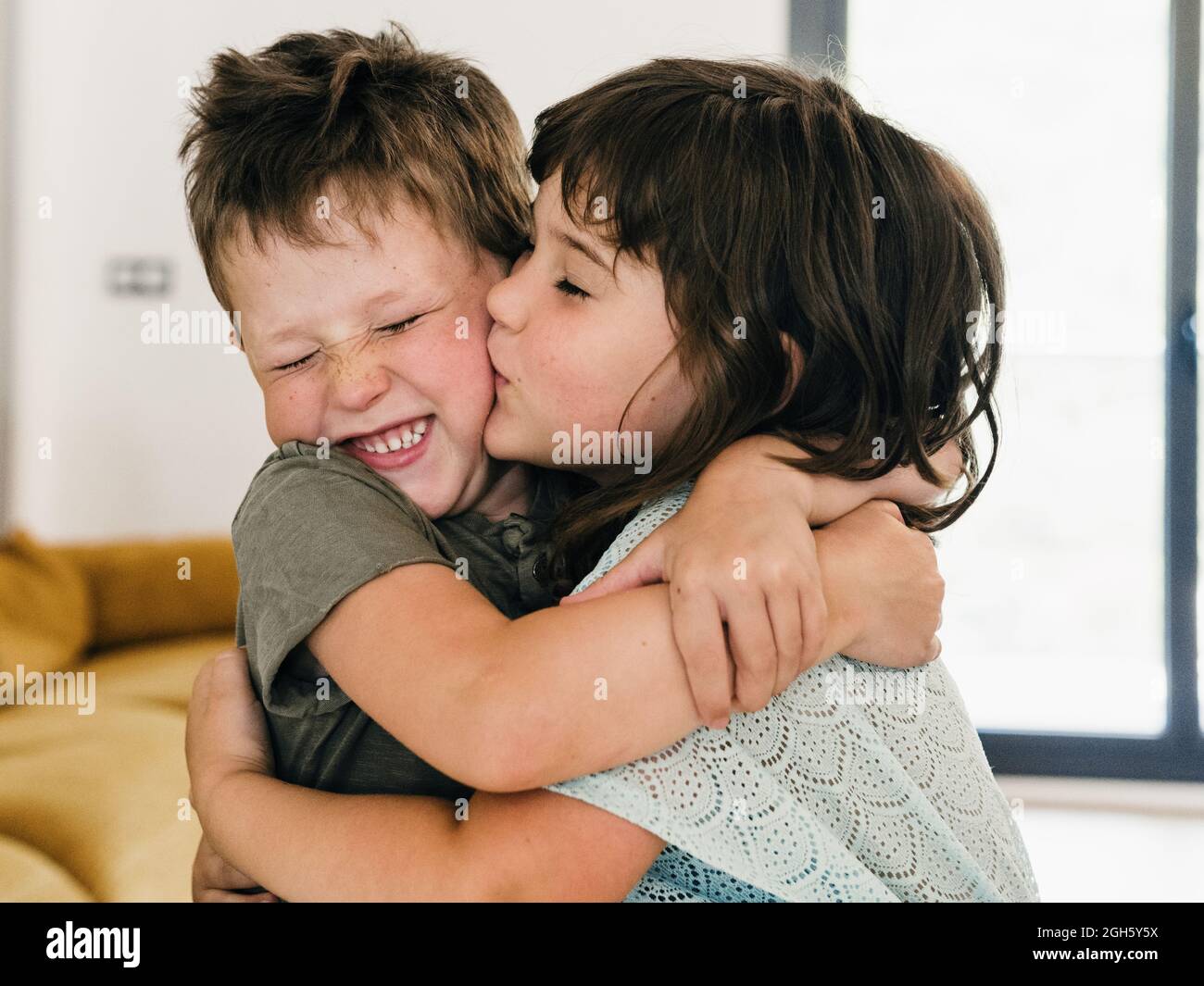 Cute content twins embracing tenderly and kissing together in living ...