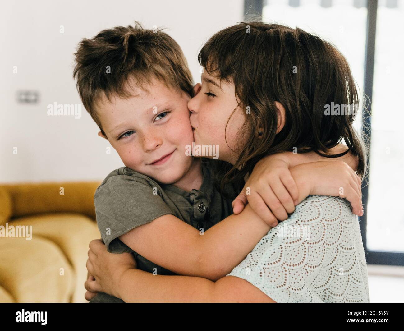 Cute content twins embracing tenderly and kissing together in living ...