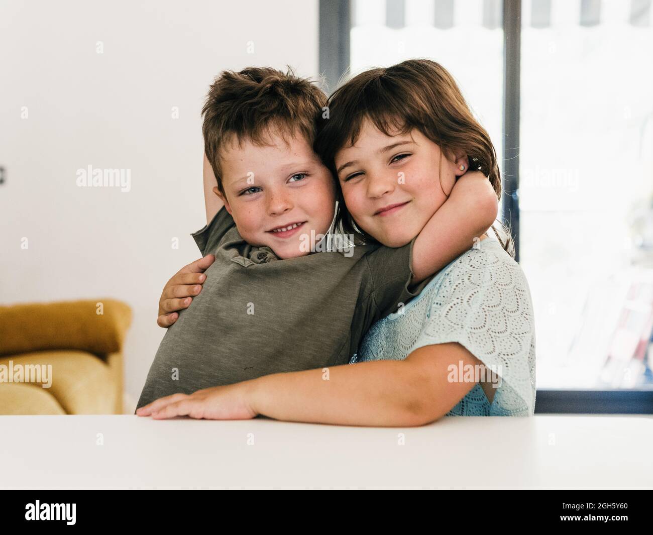 Cute content twins embracing tenderly and sitting together in living ...