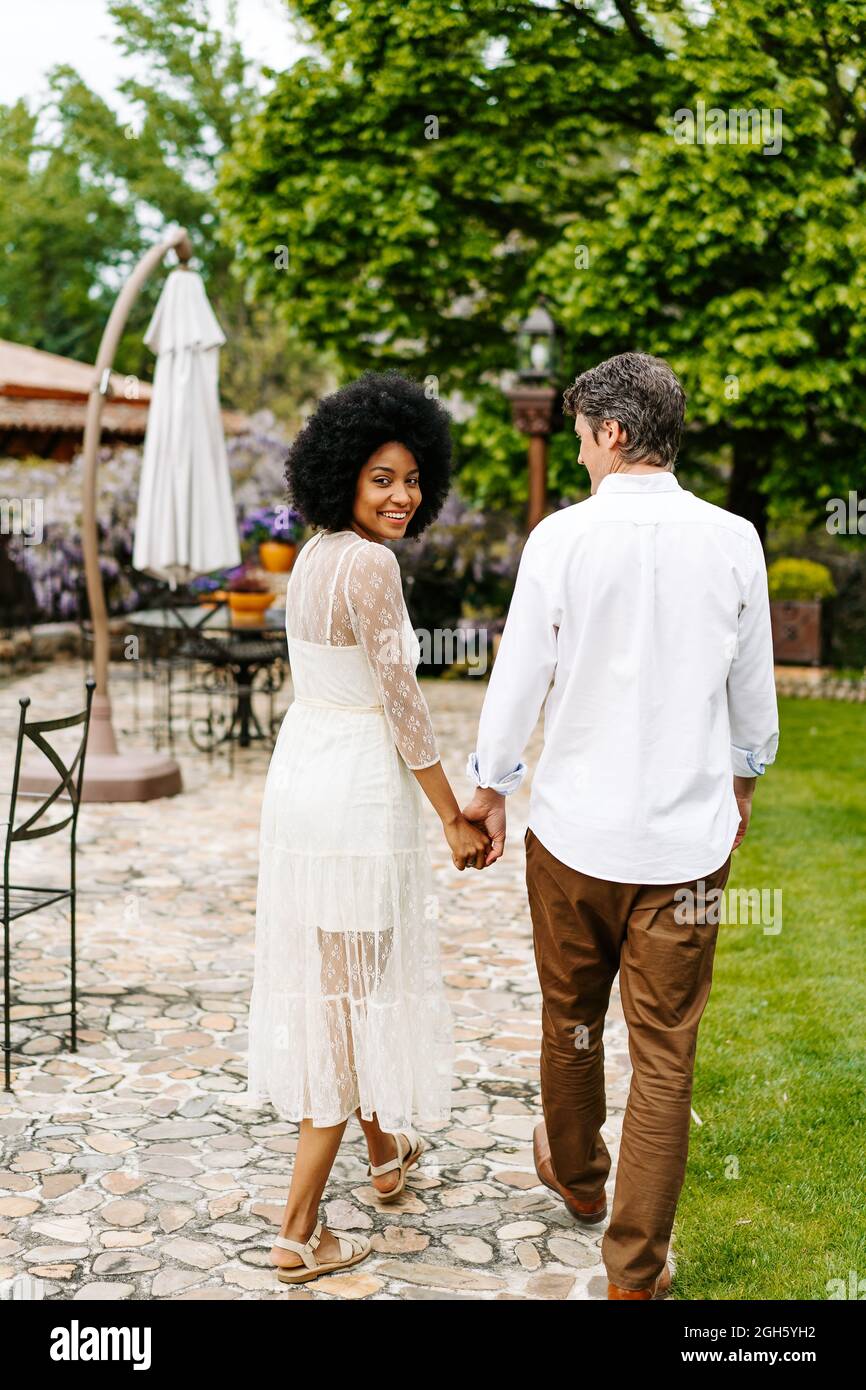 Back view of man holding hand of loving Woman looking over shoulder at ...