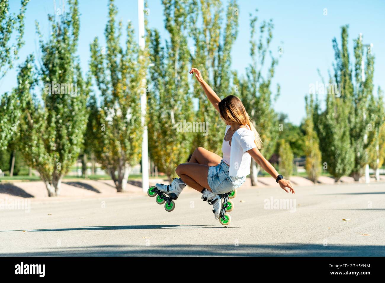 Side view of fit female balancing in rollerblades and showing one leg ...