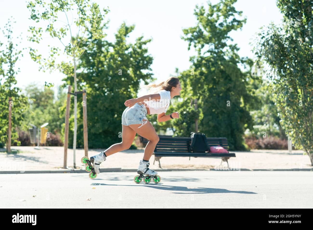 Side view of fit female in rollerblades showing stunt on road in city ...