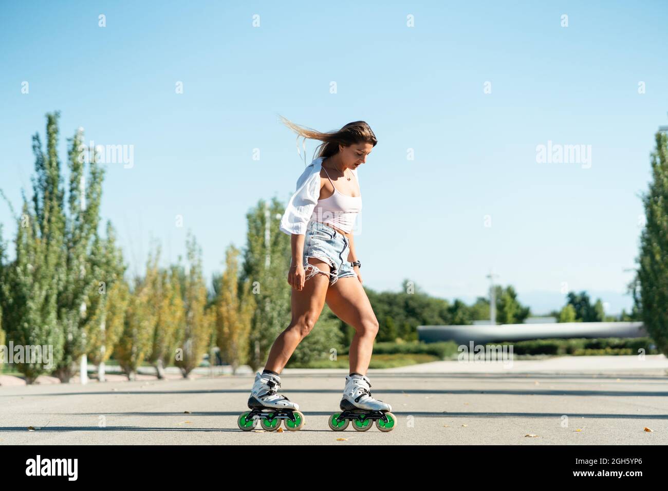 Side view of fit female in rollerblades showing stunt on road in city ...