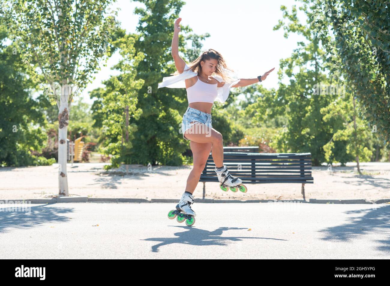 Side view of fit female in rollerblades showing stunt on road in city ...