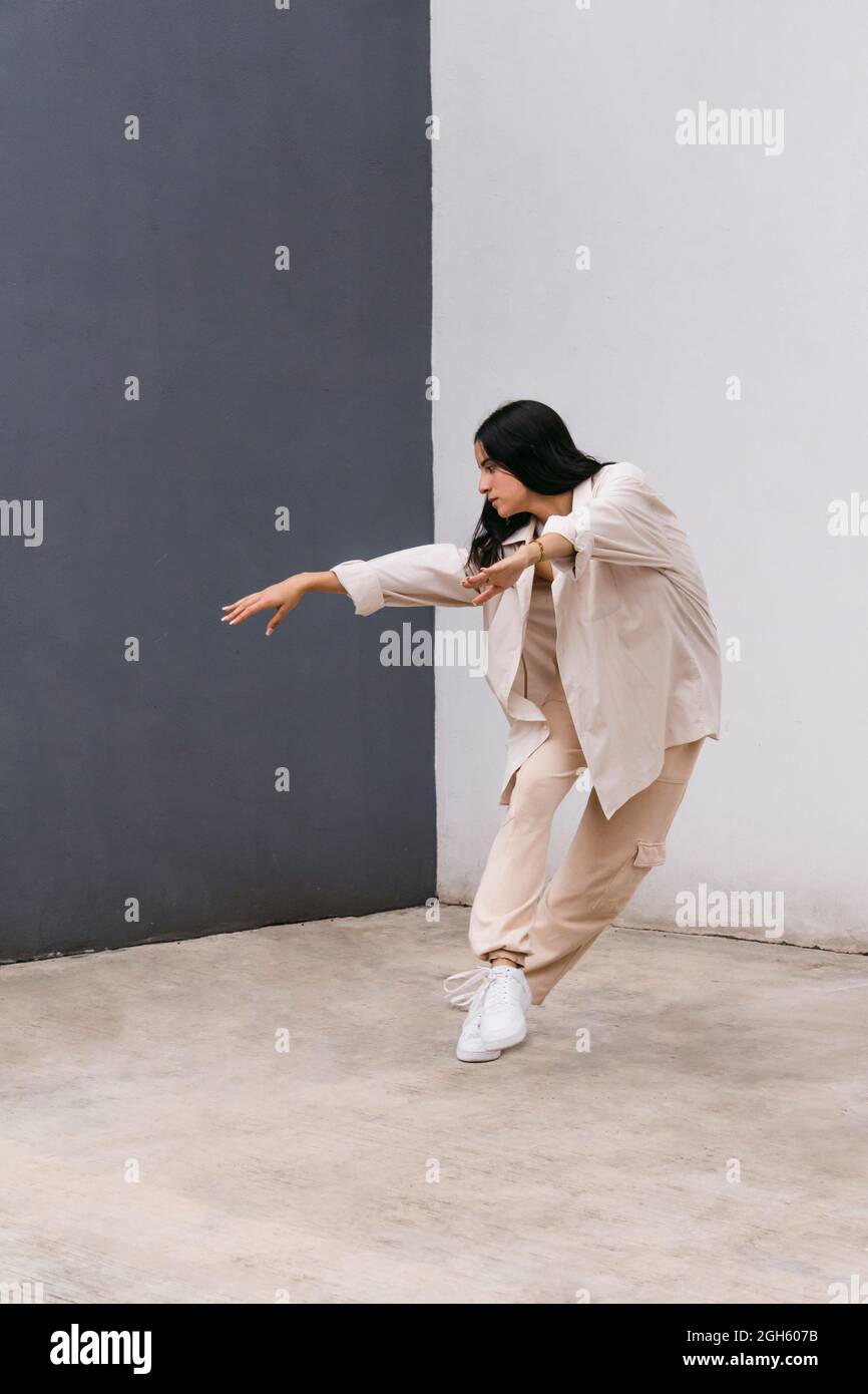 Talented female dancer moving and dancing near concrete wall in urban ...
