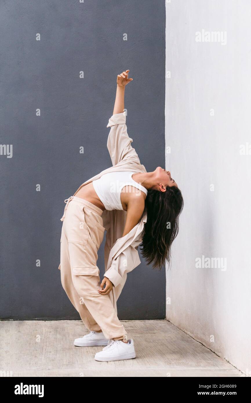 Full length creative female dancer in white clothes dancing in city ...