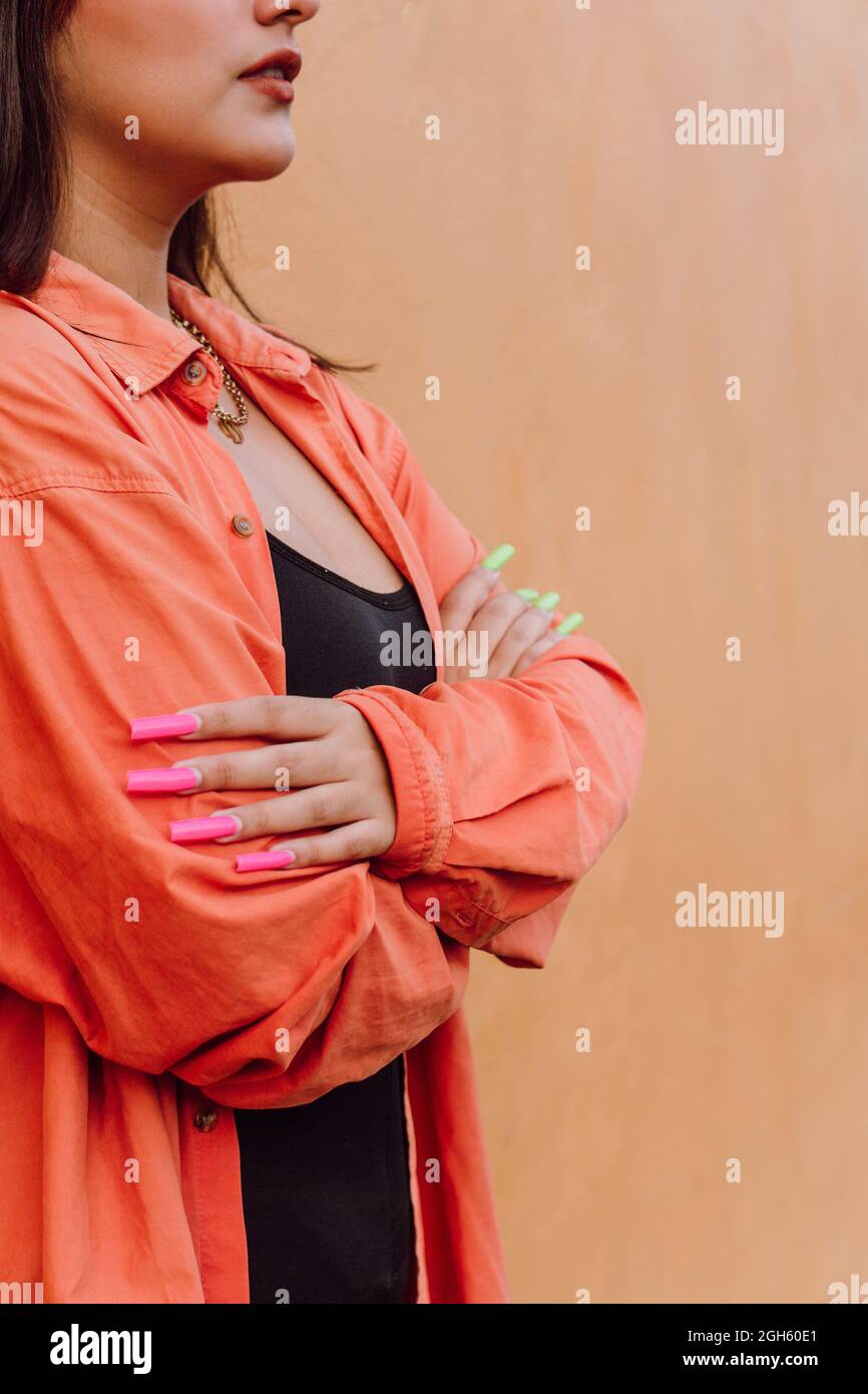 Crop unrecognizable female with colorful long nails crossing arms ...