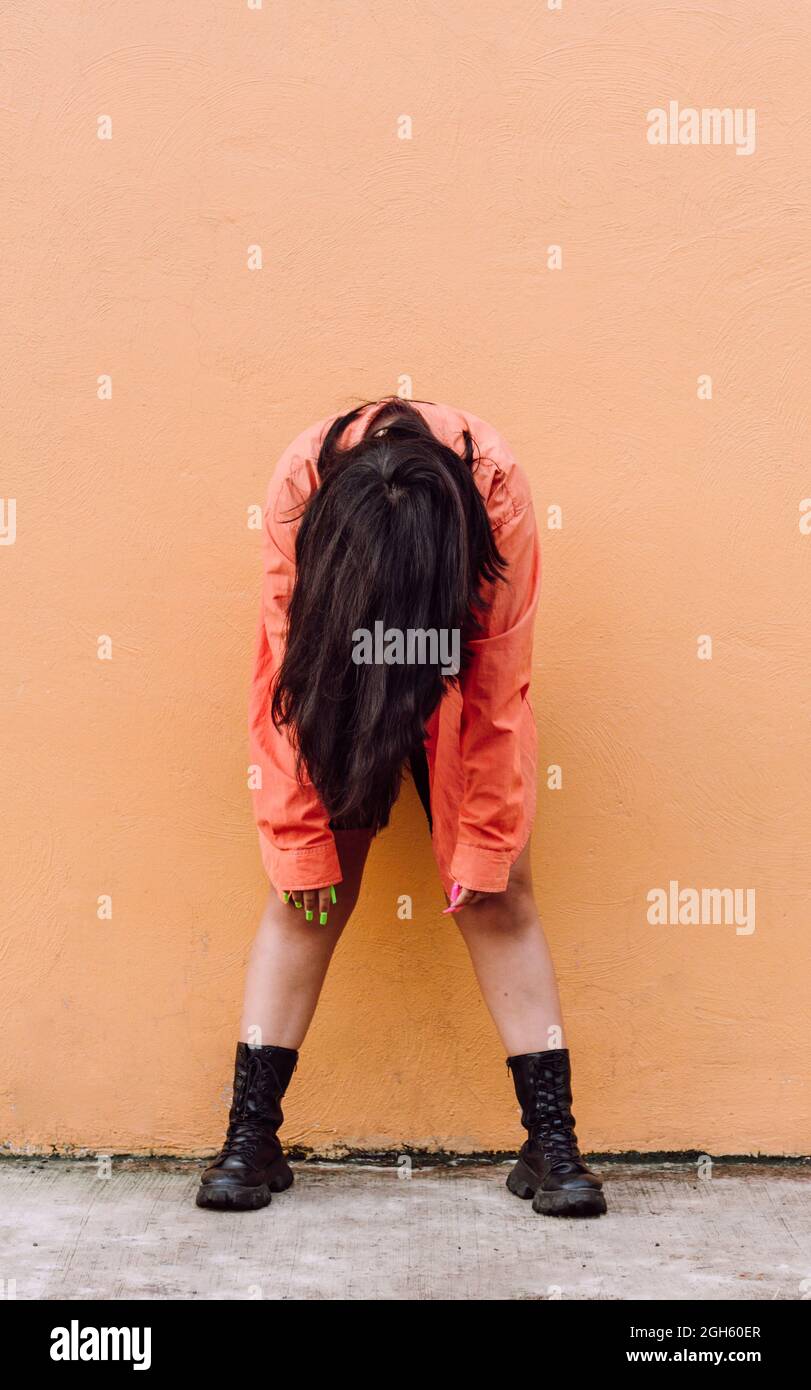 Full body of young anonymous female covering face with long brown hair ...
