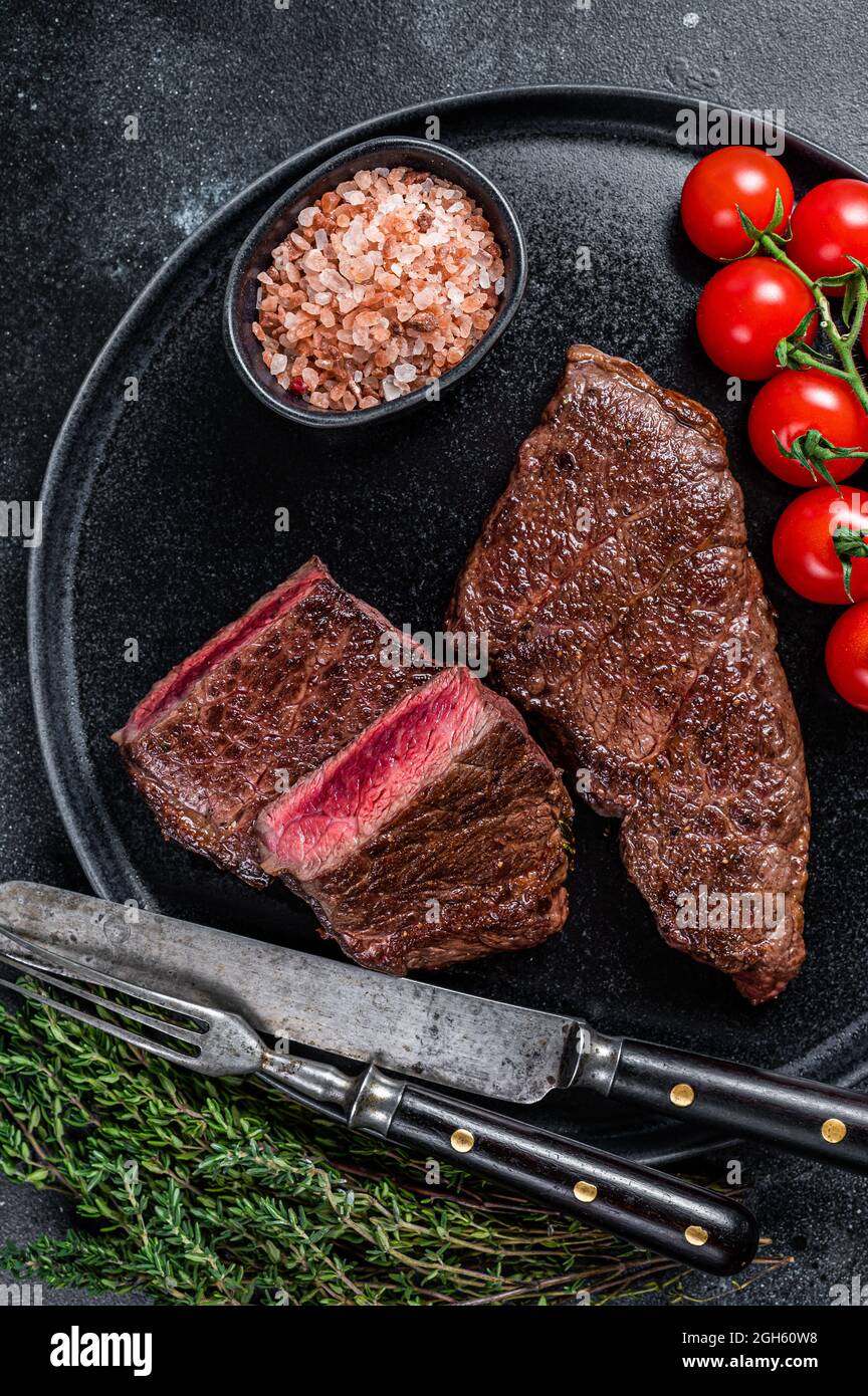 Roasted cut denver beef meat steak on a plate with thyme. Black ...