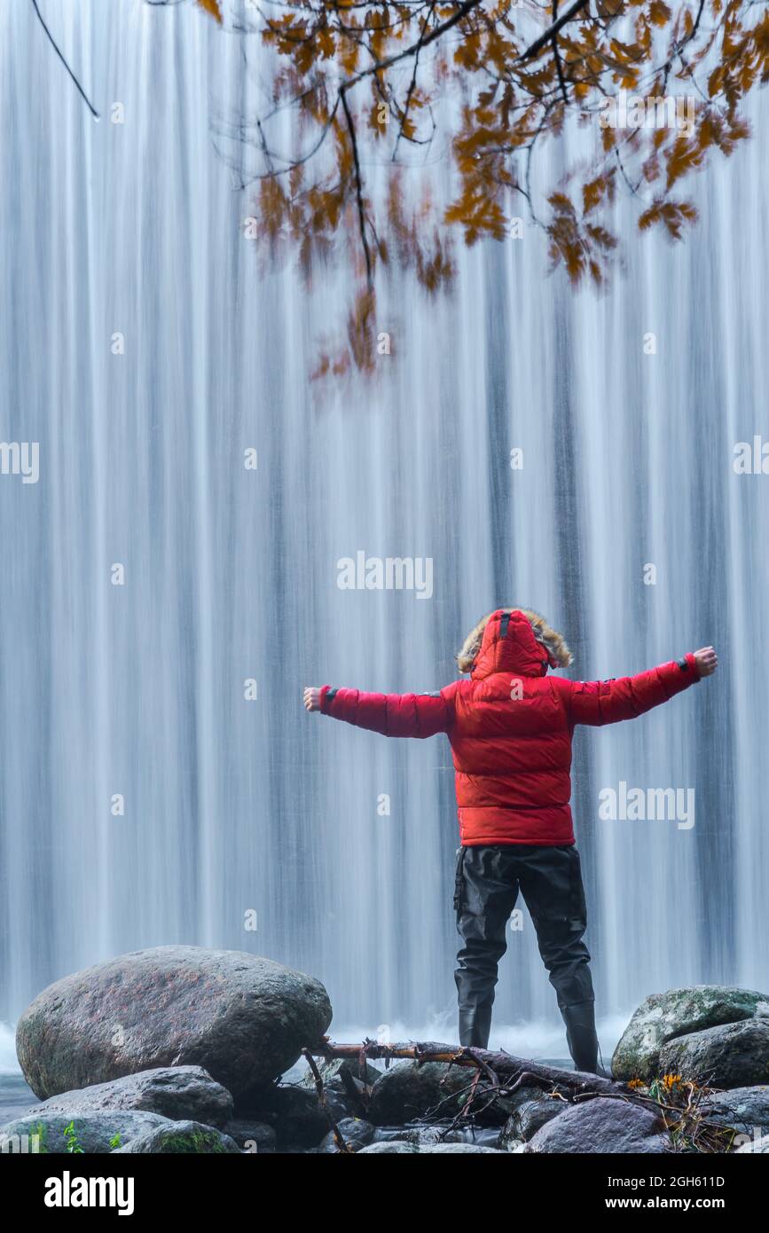 Back view of traveling male in warm clothes standing on boulder with ...