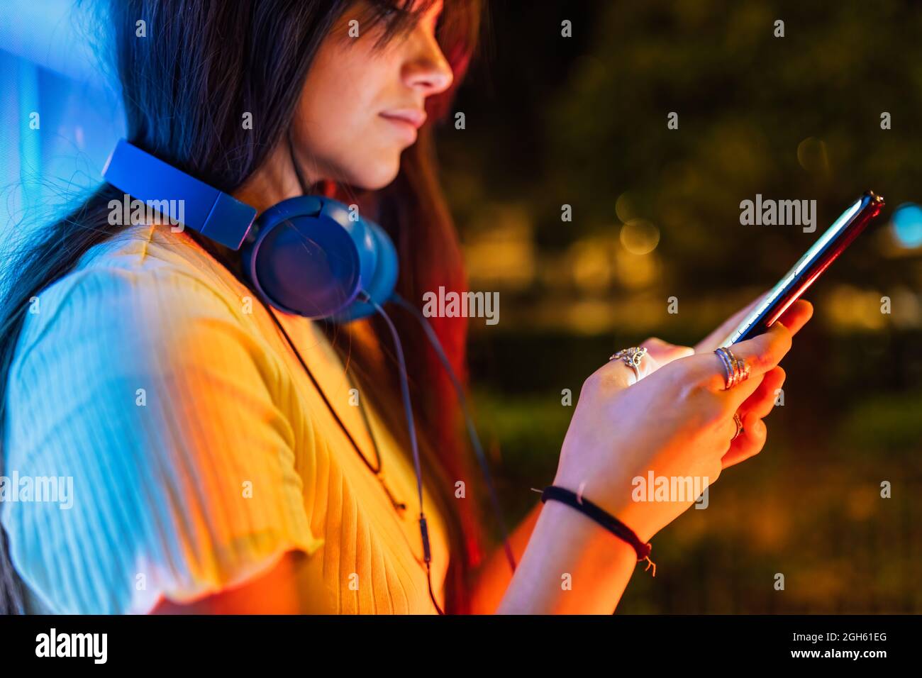 Side view of crop young female with headset text messaging on cellphone ...