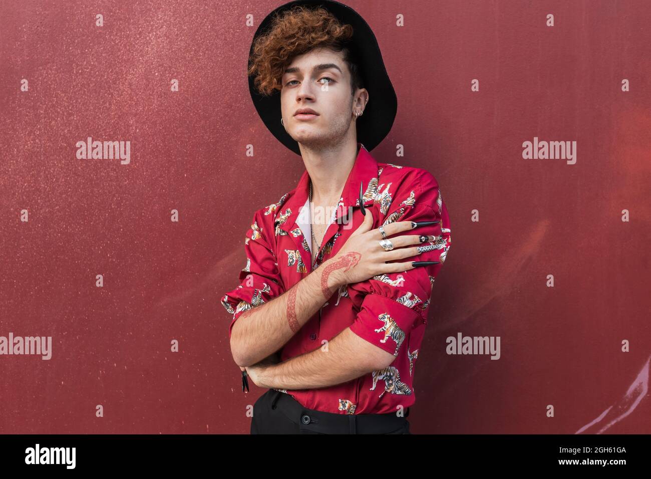 Young vain man in stylish wear standing on tiled walkway while looking ...