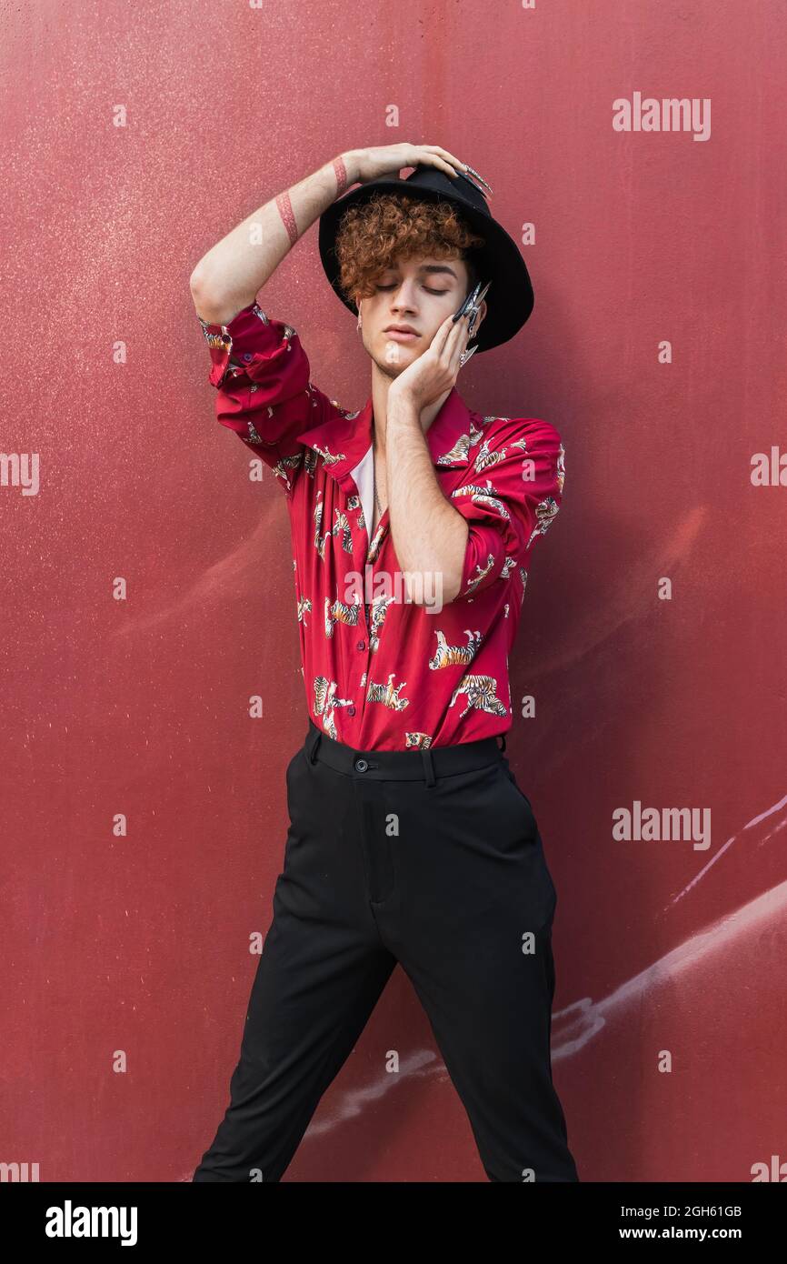 Young vain man in stylish wear standing on tiled walkway while looking ...