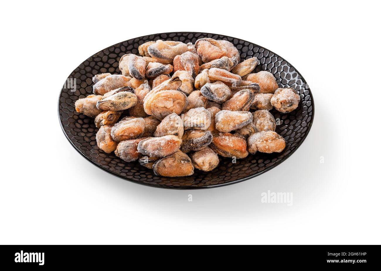 Frozen peeled mussel meat on an round black ceramic plate isolated on a ...