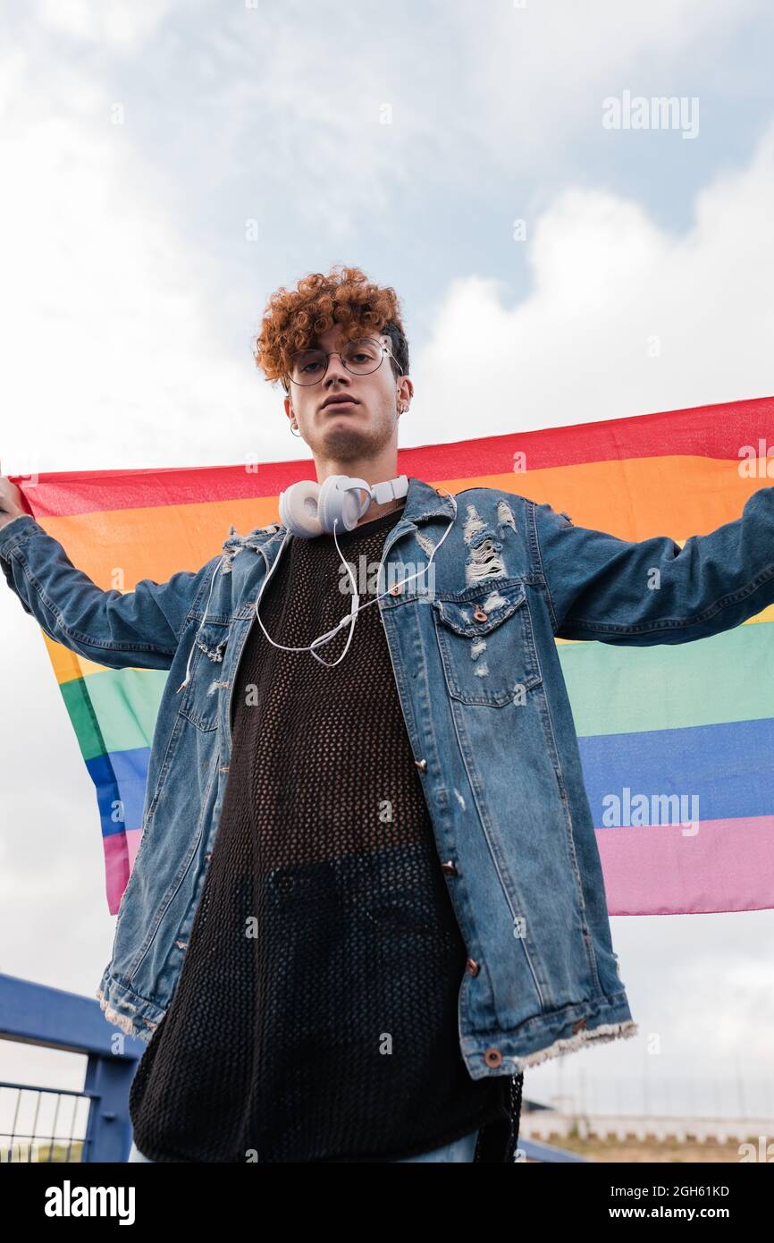 From below of serious homosexual male standing with rainbow flag in ...