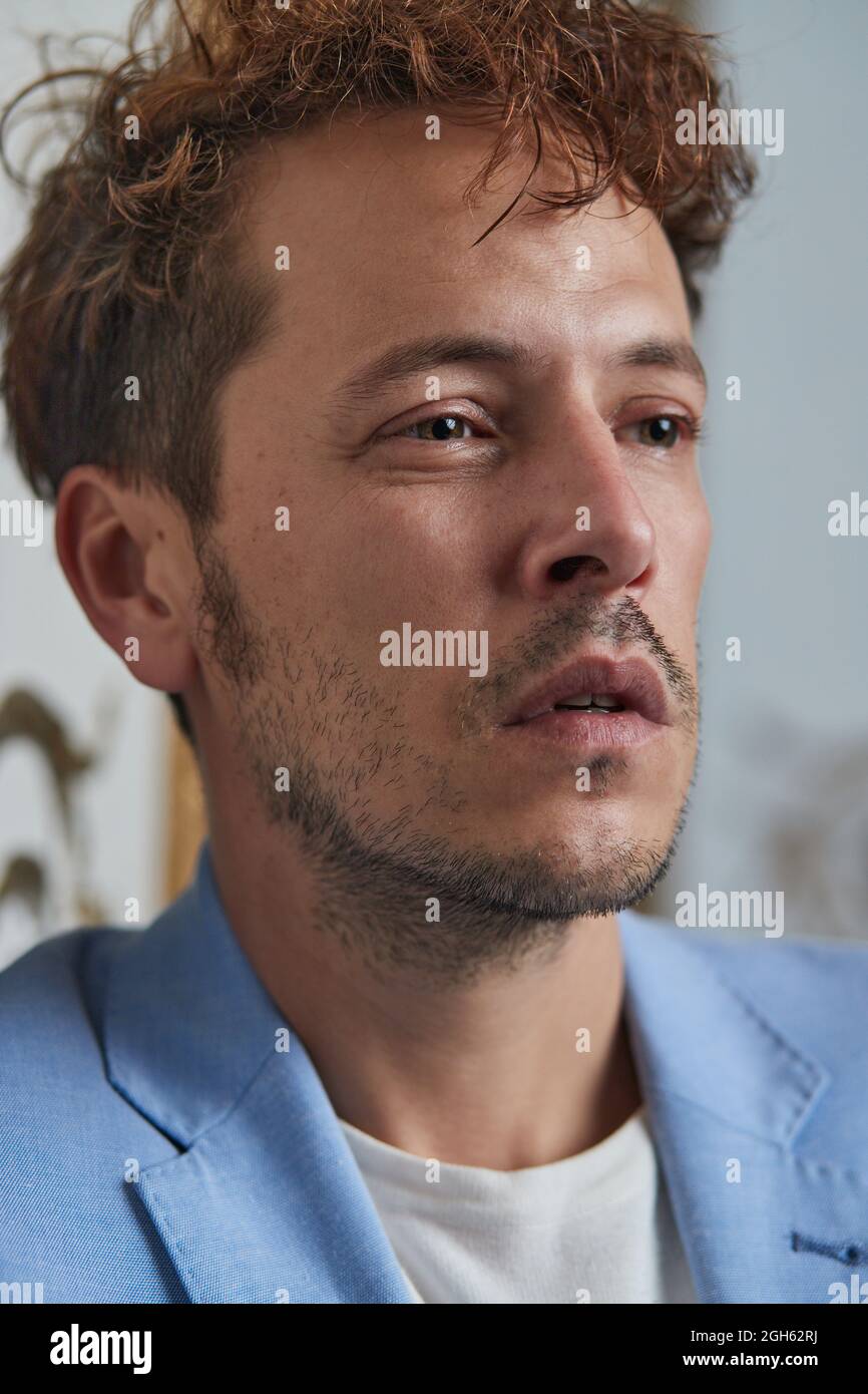Stressed male in suit standing with crossed arms and leaning on wall in ...