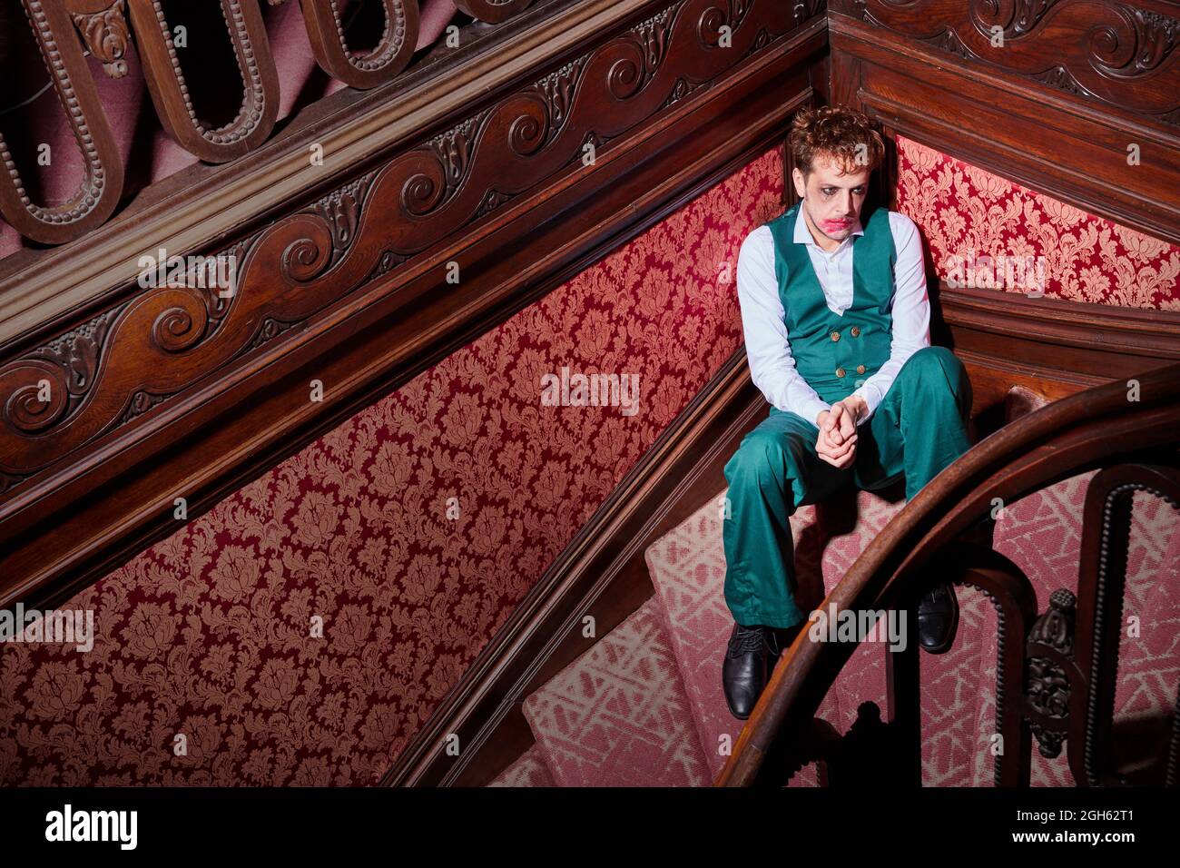 From above of eccentric male actor with smeared makeup sitting on ...