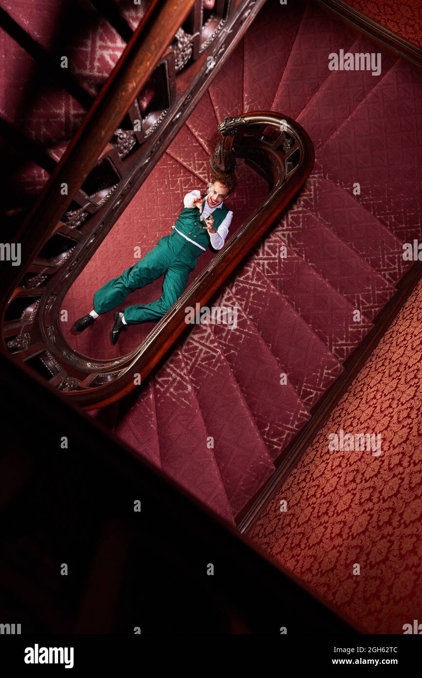 Top view of talented male actor lying on floor near staircase and ...