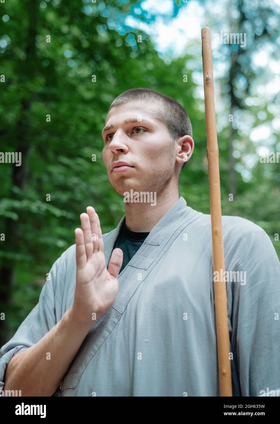 Low angle of man with stick holding hand near chest while practicing ...