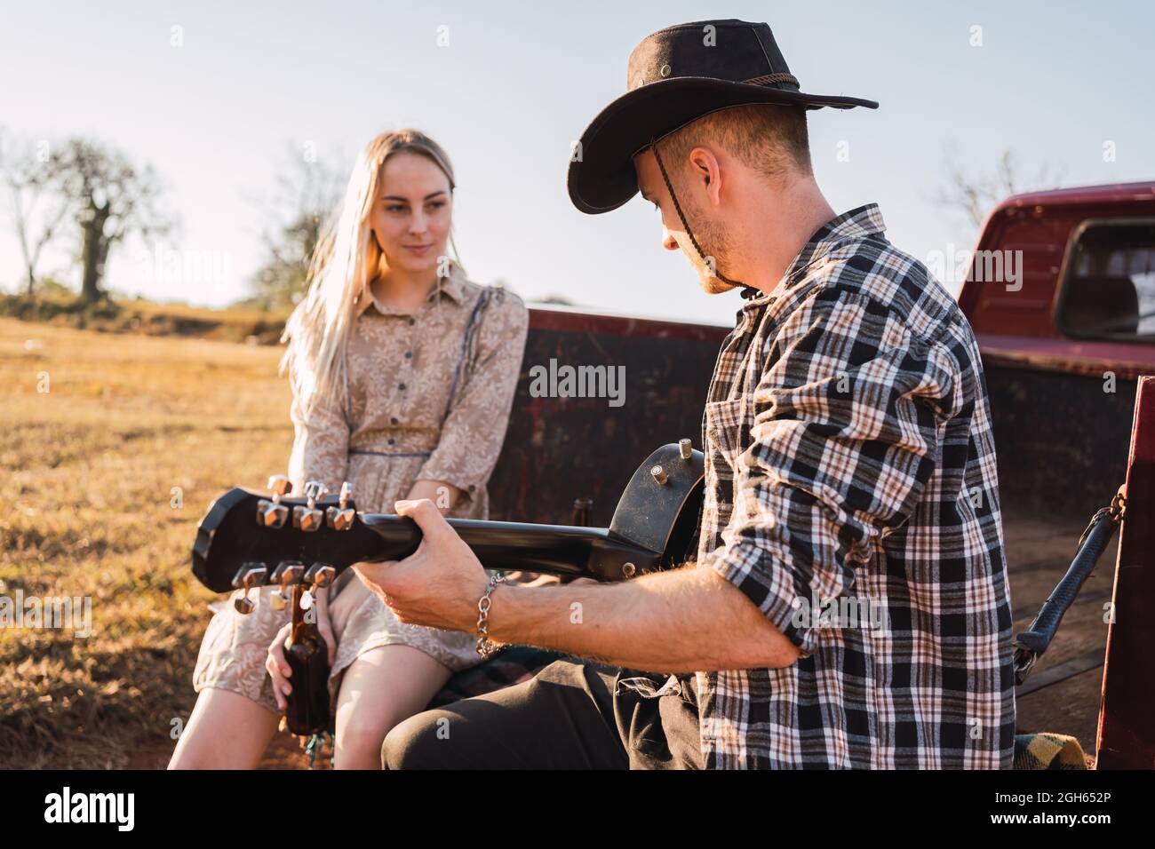 boyfriend in cowboy hat playing acoustic guitar while sitting with ...