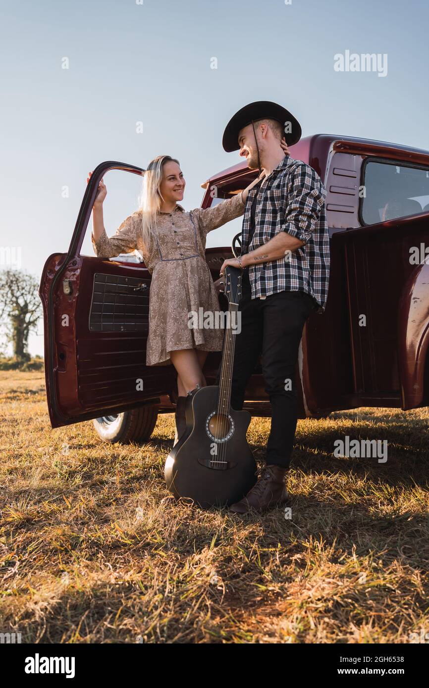 boyfriend in cowboy hat with acoustic guitar while standing with ...