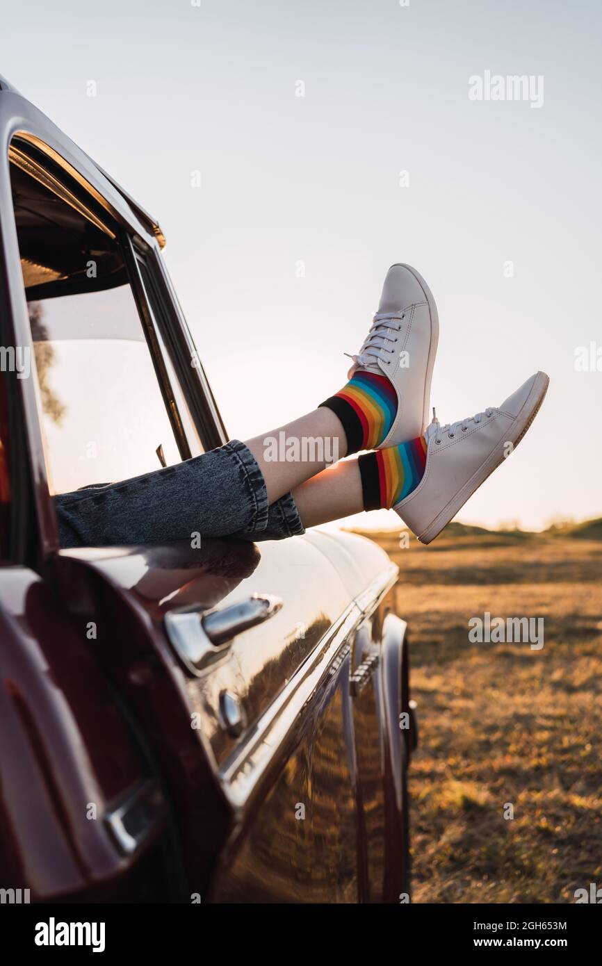 Side view of crop female chilling in vintage car with legs sticking out ...