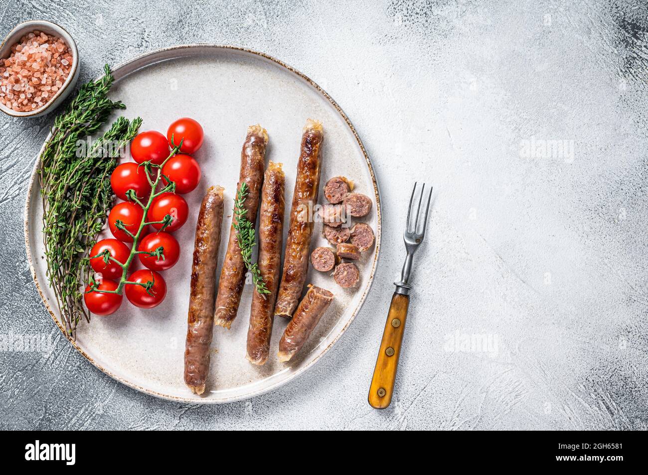 Grilled lamb meat sausage on a plate with herbs and tomato. White ...