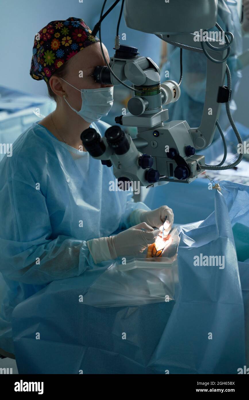 Attentive female doctor in surgical uniform and sterile mask looking ...