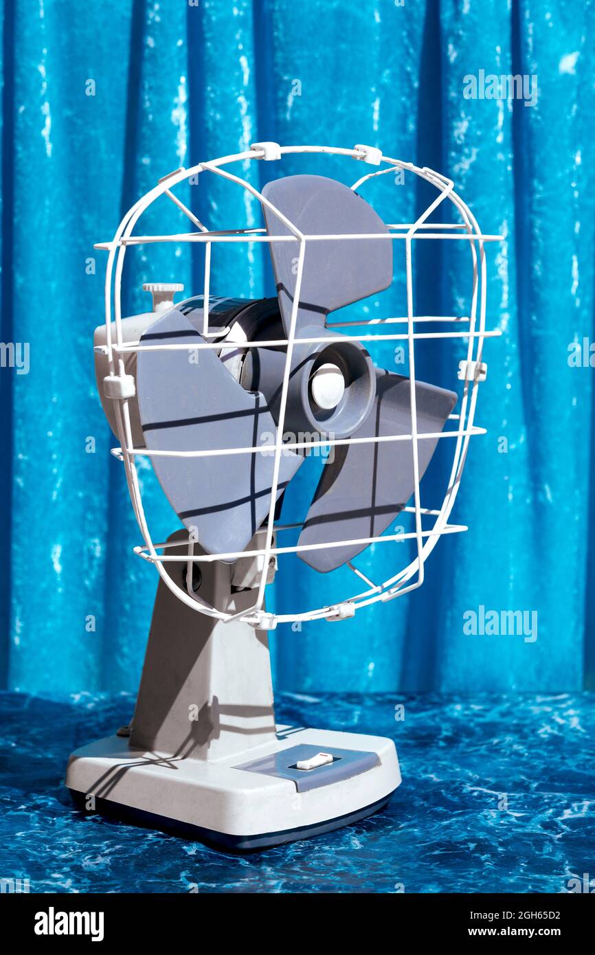 Old fashioned fan placed on marble table in studio on bright blue ...