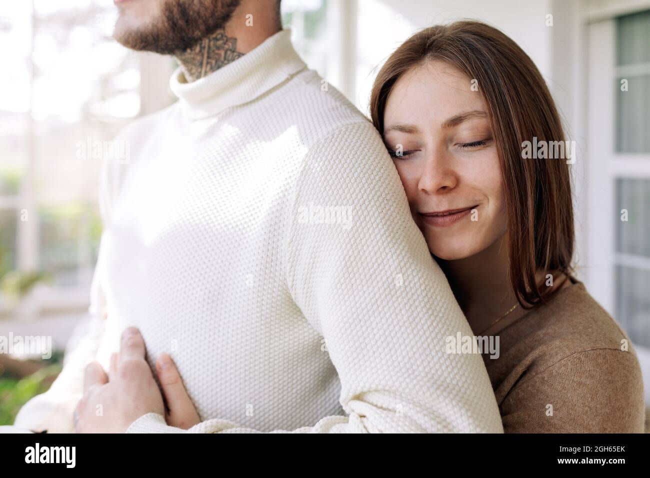 Side view of cheerful female embracing bearded male beloved while ...