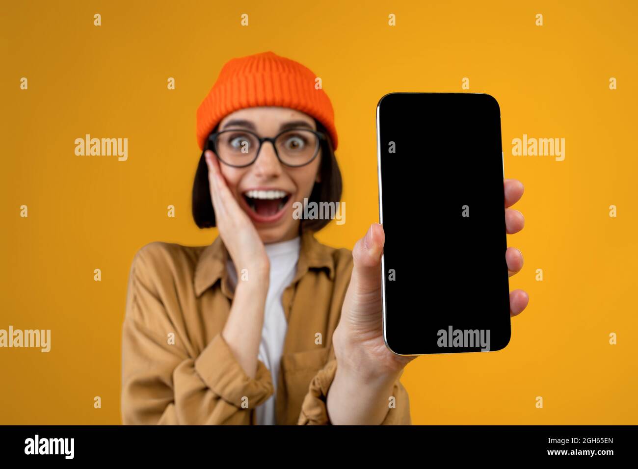 Wow, amazing useful app. Surprised young lady holding smartphone with ...