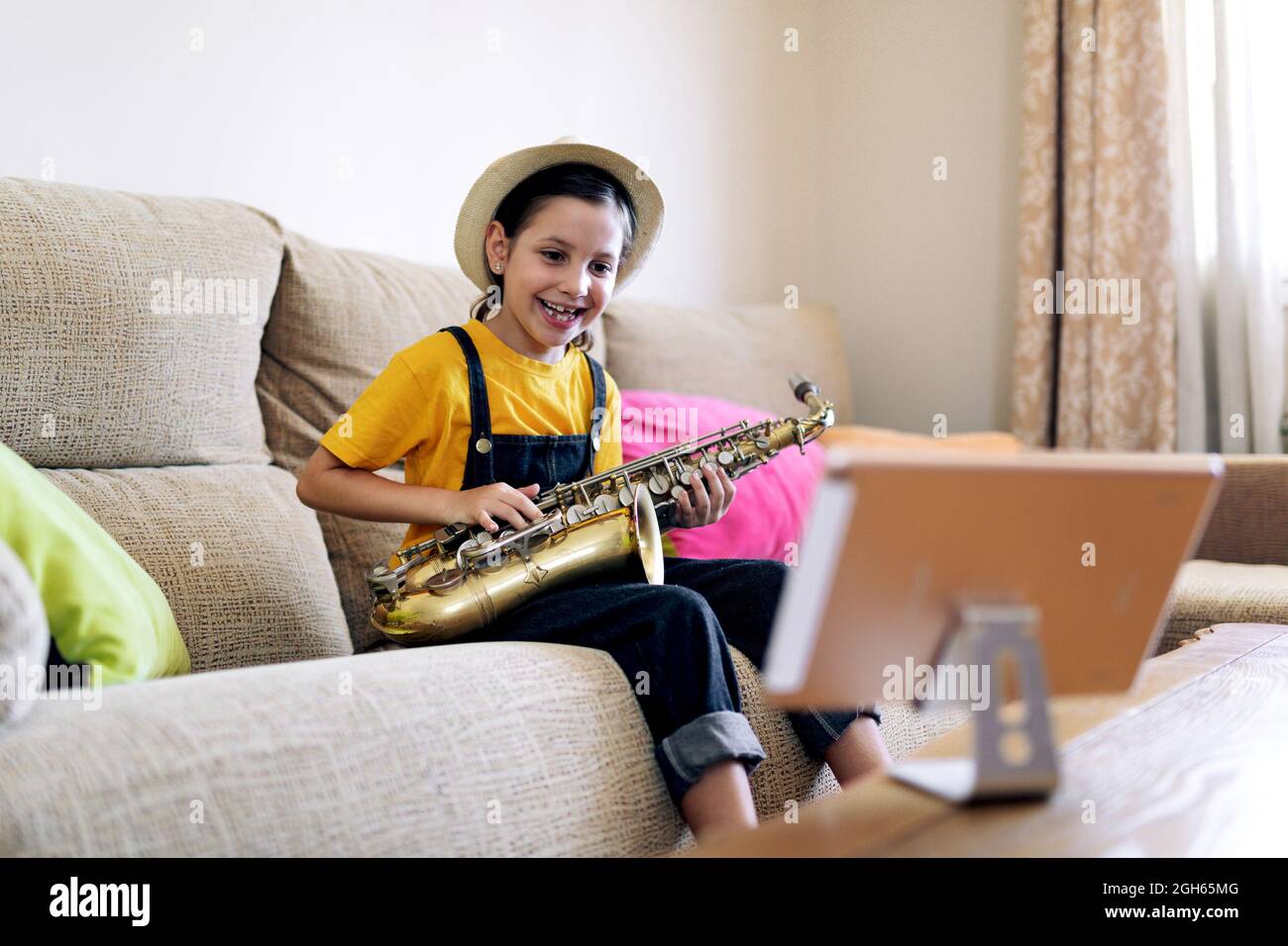 Mindful child with saxophone and with a tablet on couch Stock Photo - Alamy