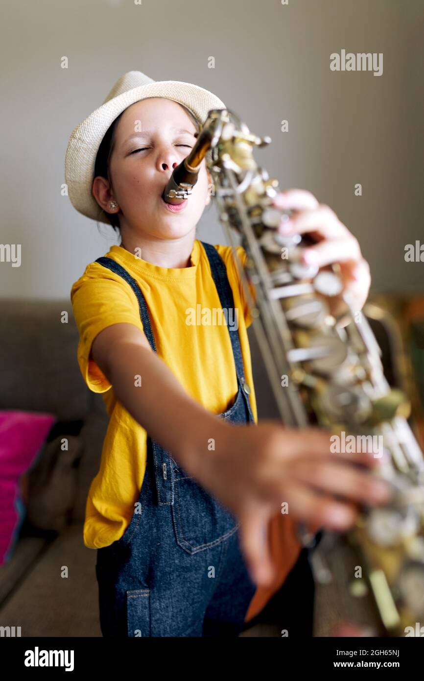 Child with saxophone in living room standing against window in room ...