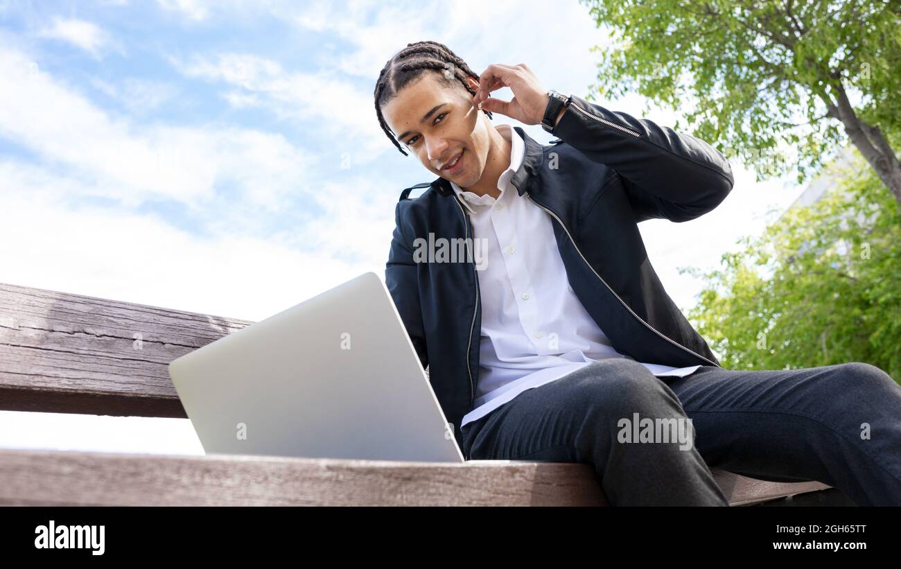 From below of happy ethnic male freelancer with braided hairstyle ...