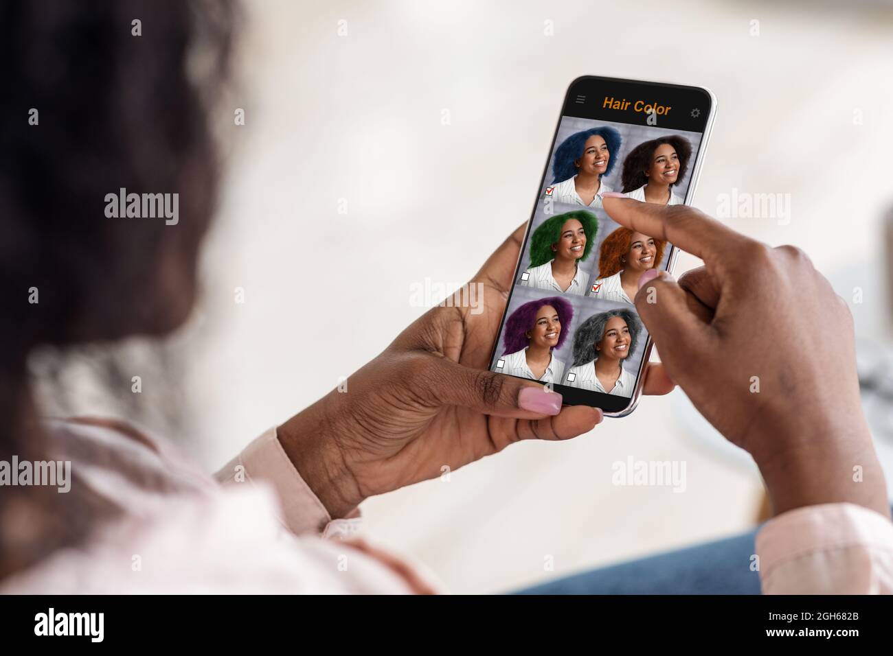 Black lady checking hair color simulation mobile app on smartphone ...