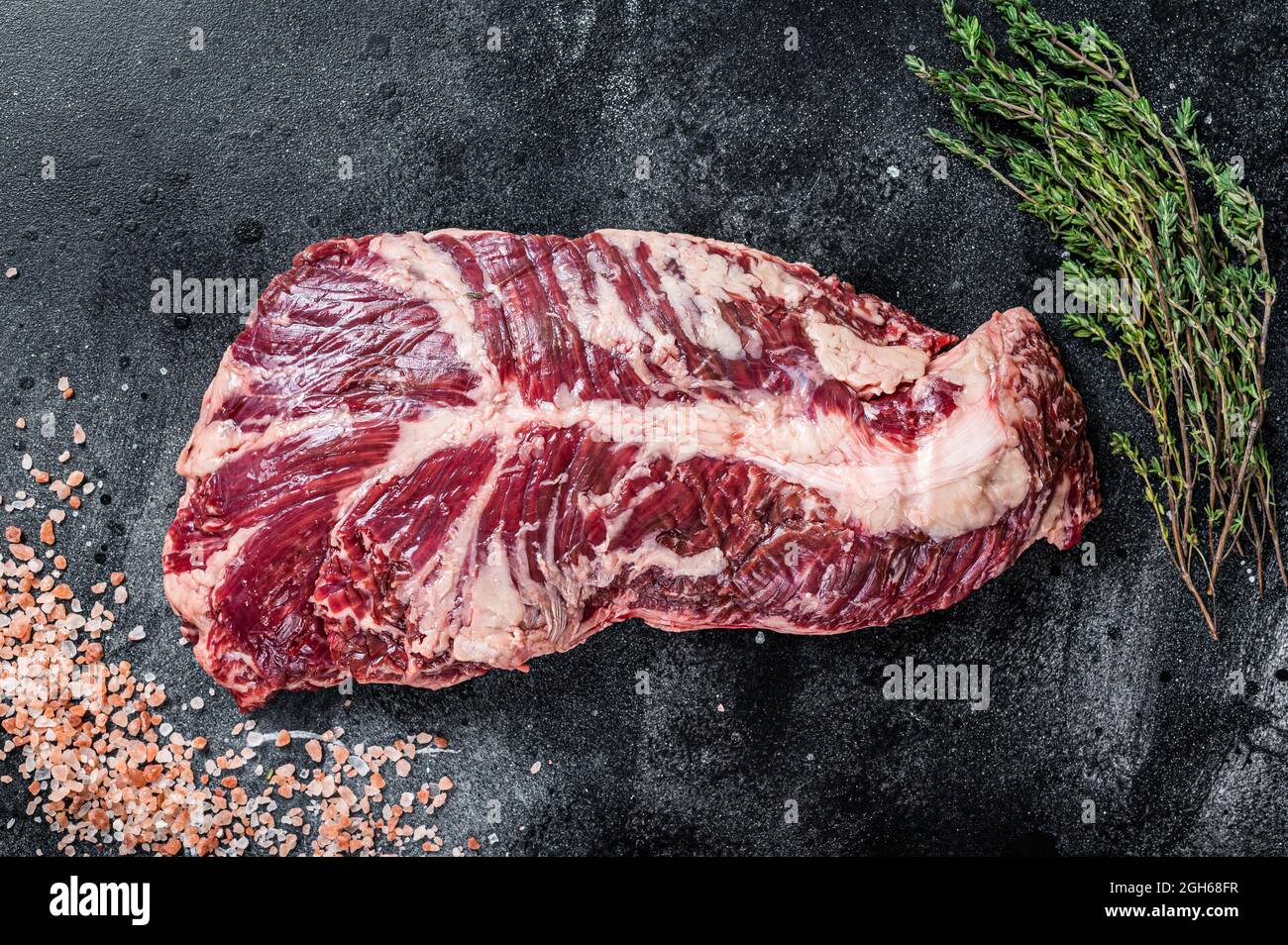 Hanger or onglet raw beef meat steak on butcher table with herbs. Black ...