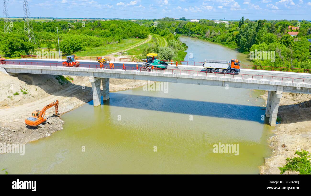 Above view, sideways, on workers and machinery for laying asphalt ...