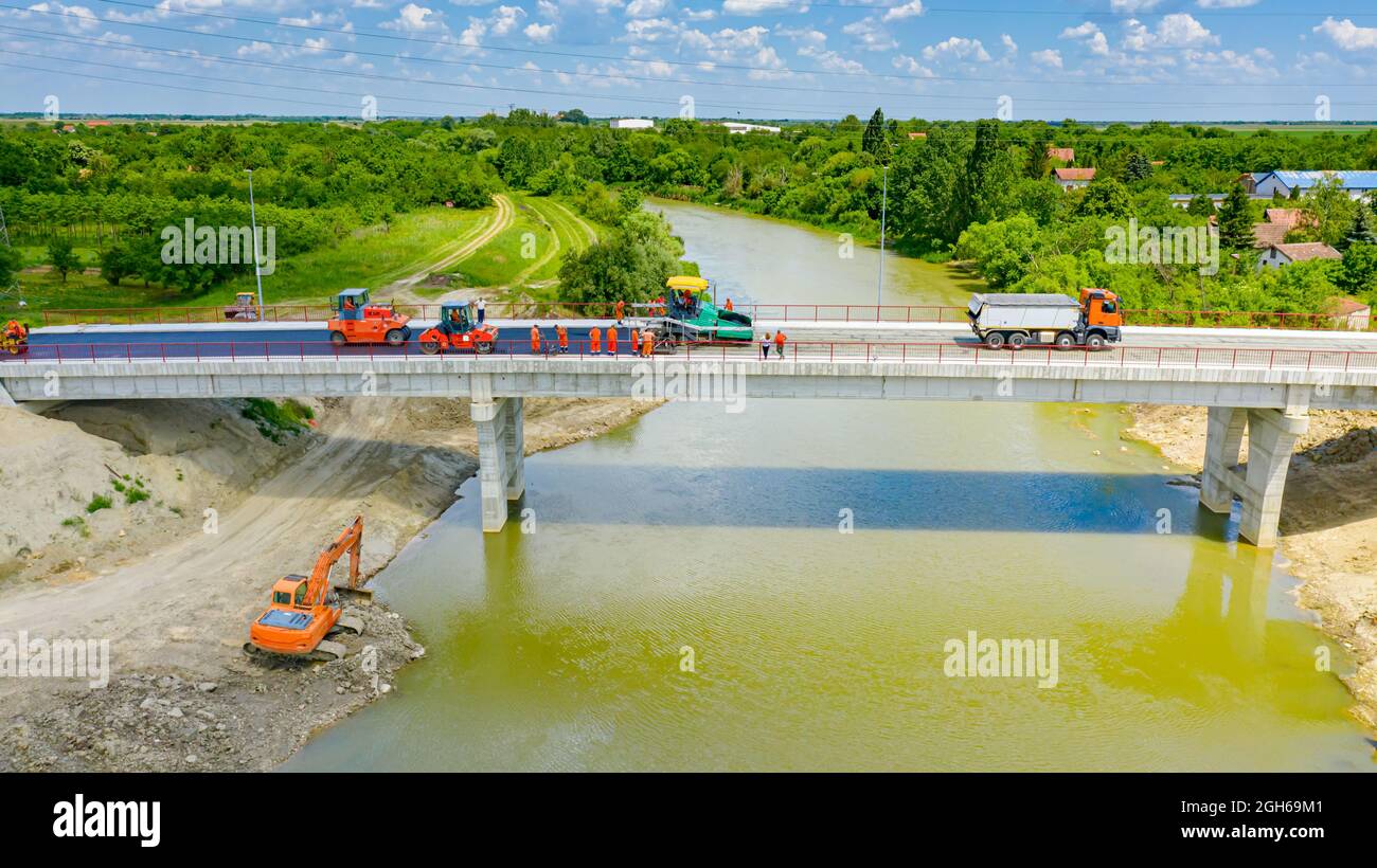 Above view, sideways, on workers and machinery for laying asphalt ...