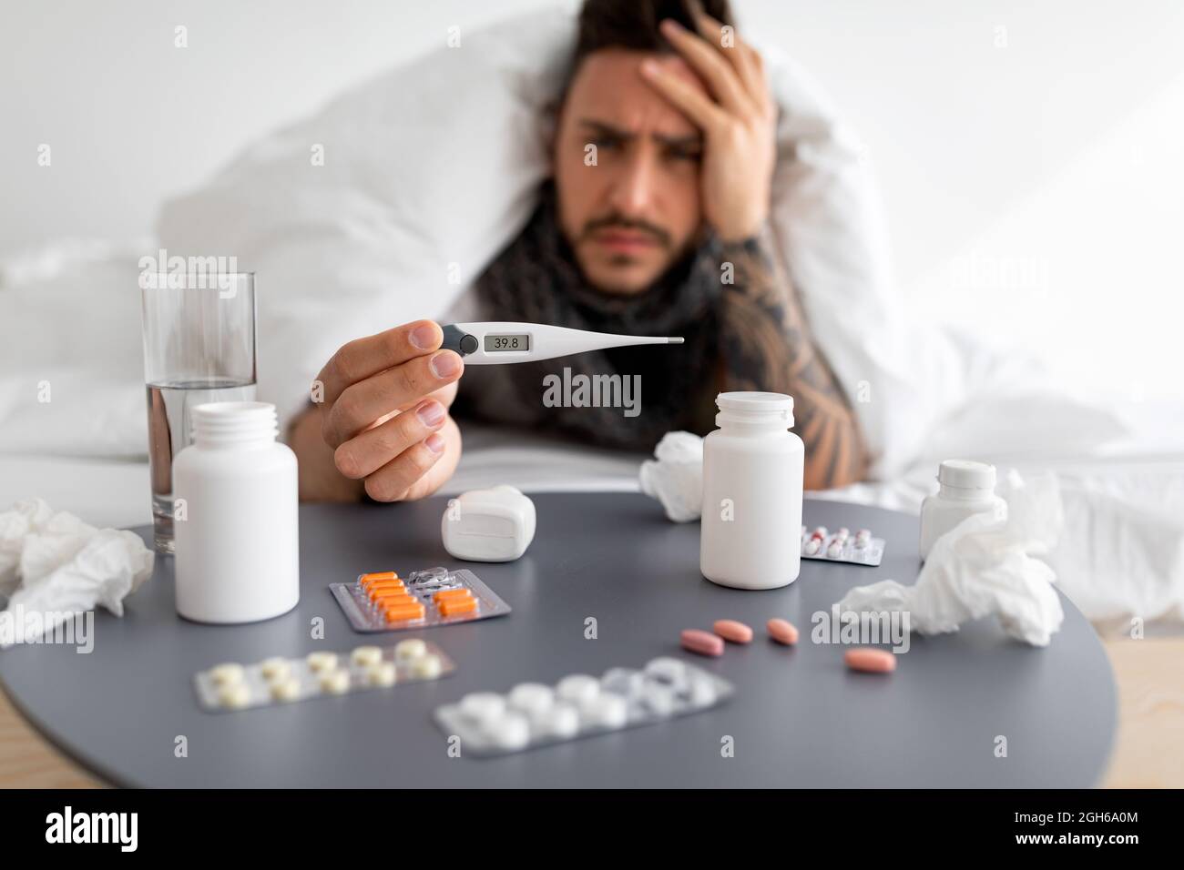 Coronavirus and influenza symptoms. Sick guy showing thermometer with ...