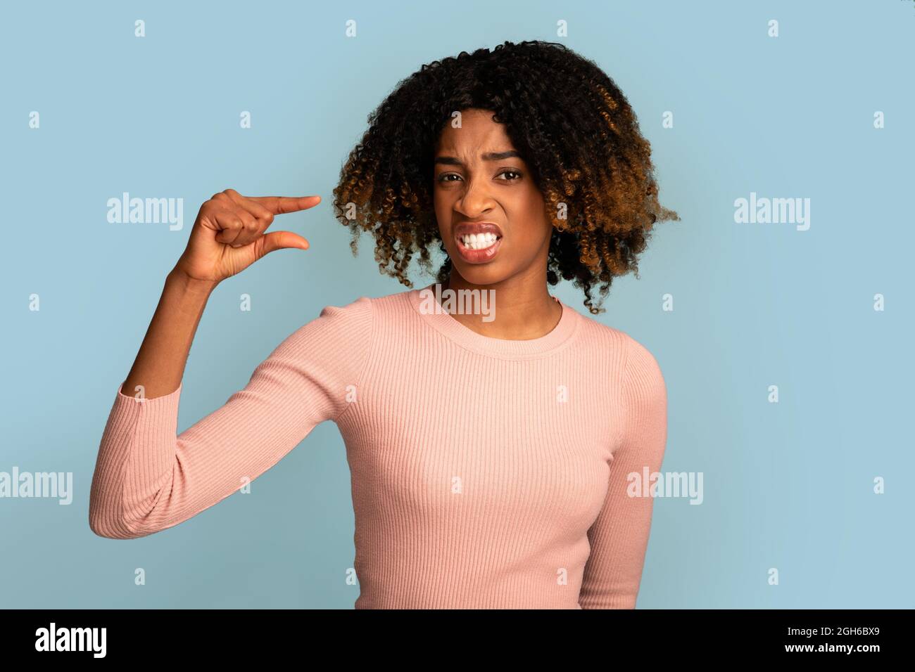 Displeased Black Woman Measuring Small Invisible Object With Fingers ...