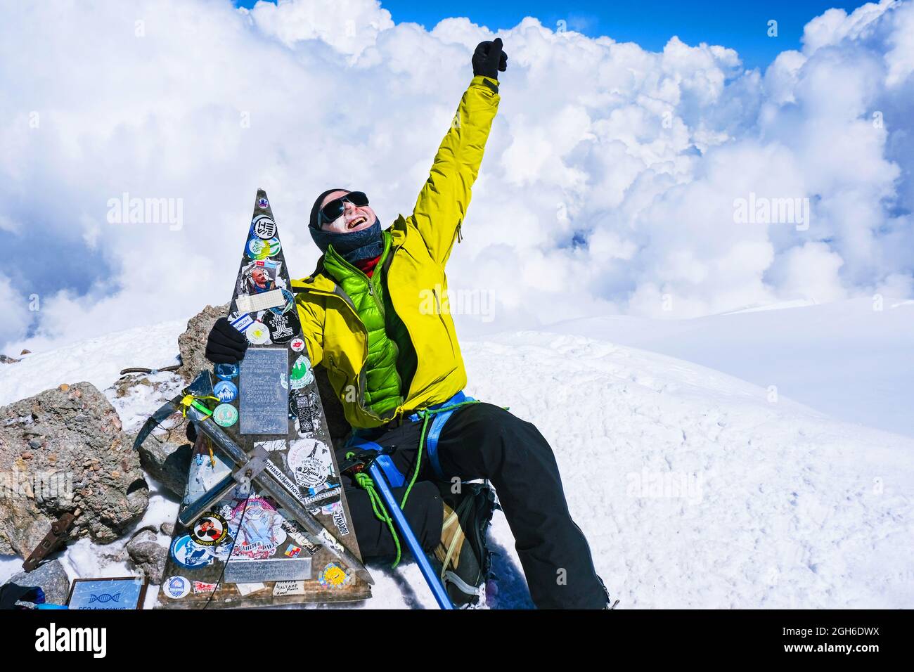 Man in yellow jacket sitting in snow on the top of mountain Stock Photo ...