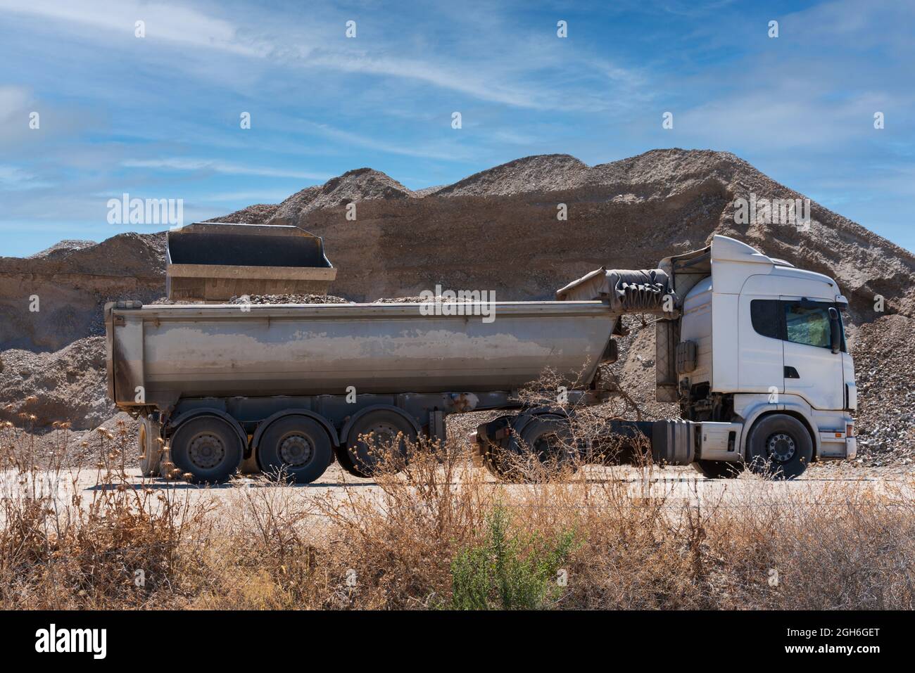 Tipper truck in a gravel pit just loaded by an excavator Stock Photo ...