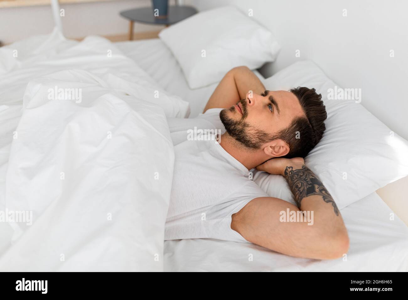 Thoughts in head not let fall asleep. Millennial man lying in bed and ...